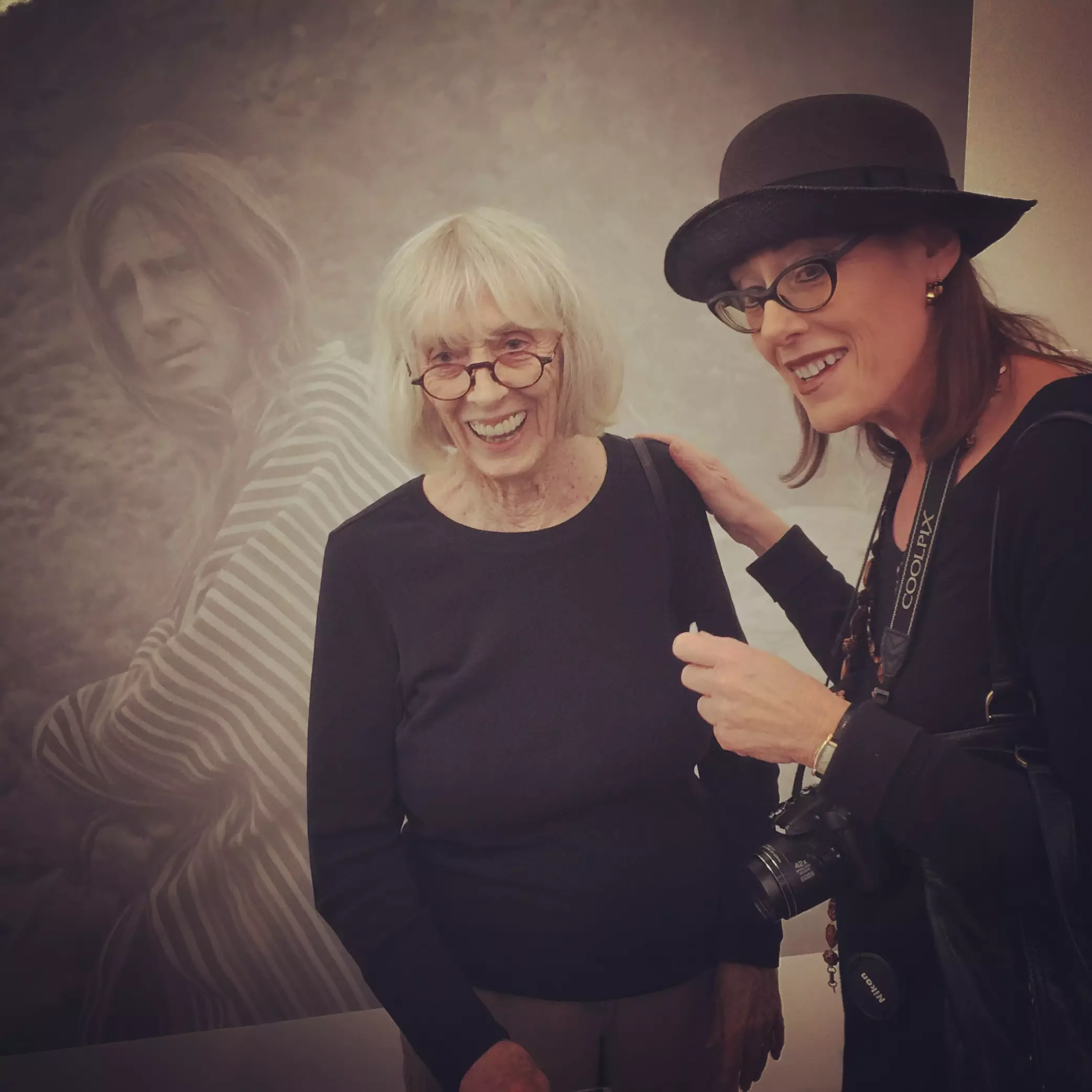 Shirley Berman z fotografką Ellen Berman (bez związku) obok zdjęcia ściennego jej męża przy wejściu do Galerii Kohn na Wallace Berman: American Aleph. fot. M Dooley.